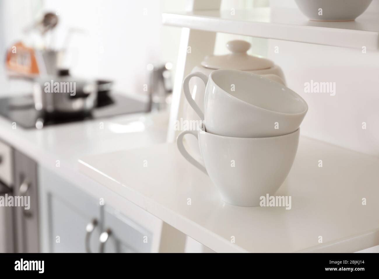 Cups on shelf in modern kitchen Stock Photo - Alamy