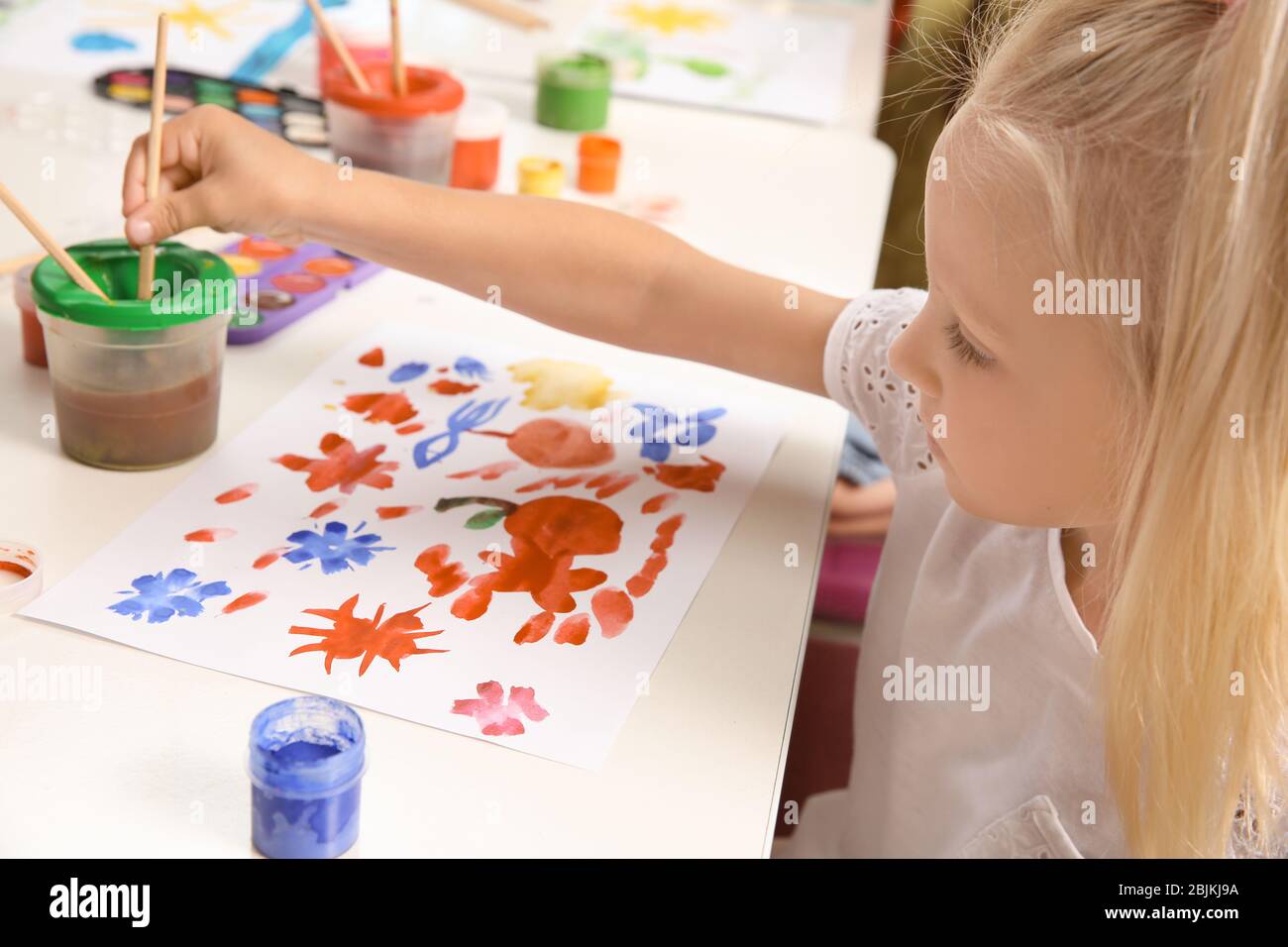 Little girl at painting lesson in classroom Stock Photo - Alamy