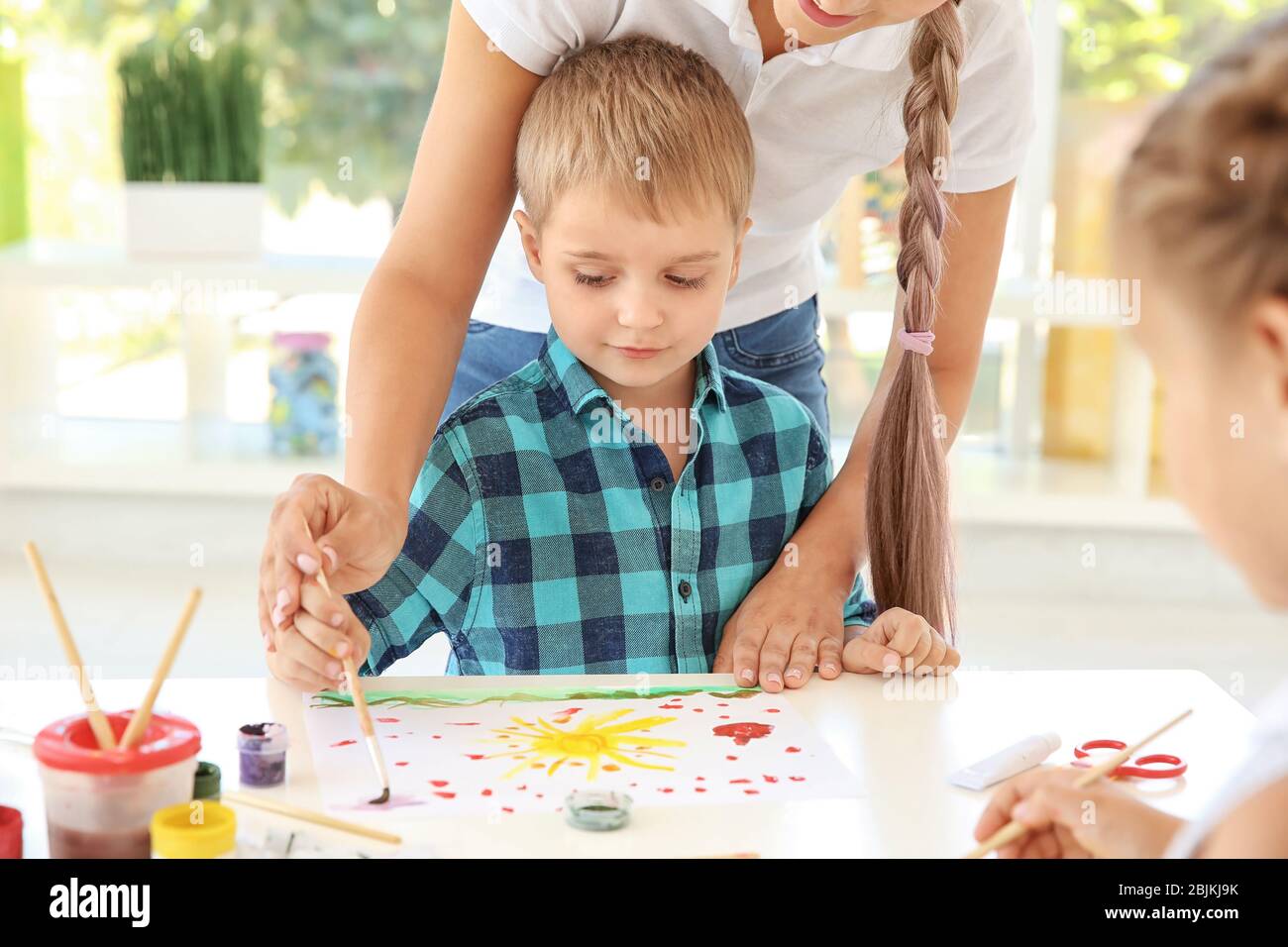 Little boy with teacher at painting lesson in classroom Stock Photo - Alamy