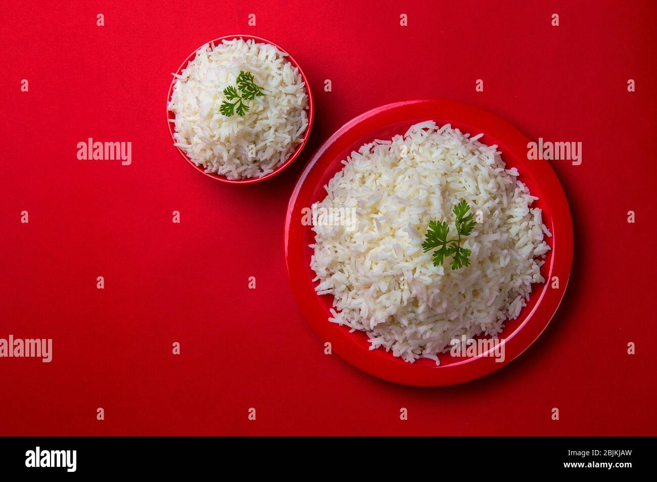 Cooked plain white basmati rice in bowl and plate on red background ...