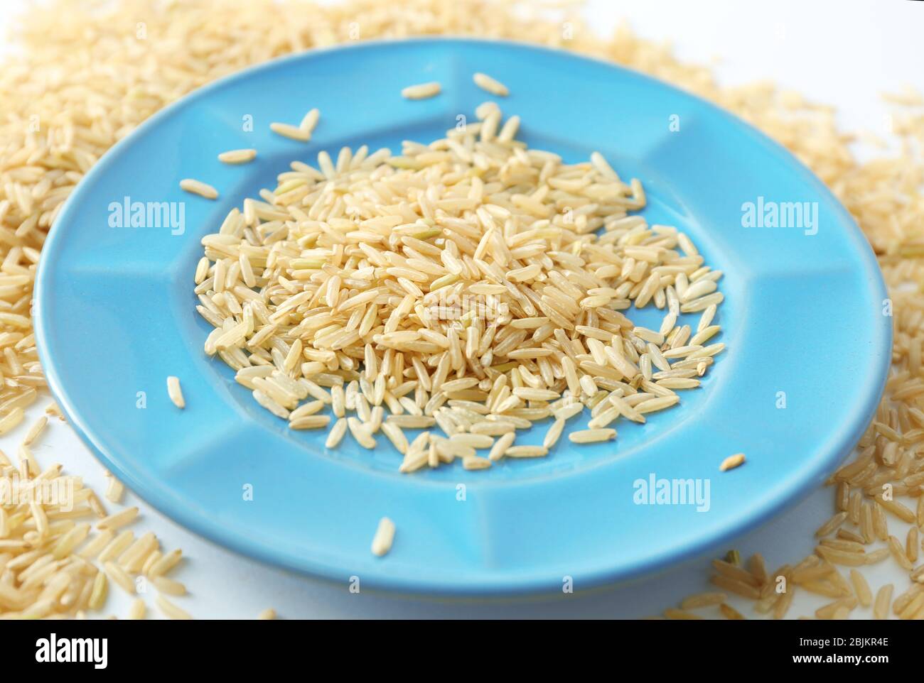 Plate of long grain brown rice on white background Stock Photo - Alamy