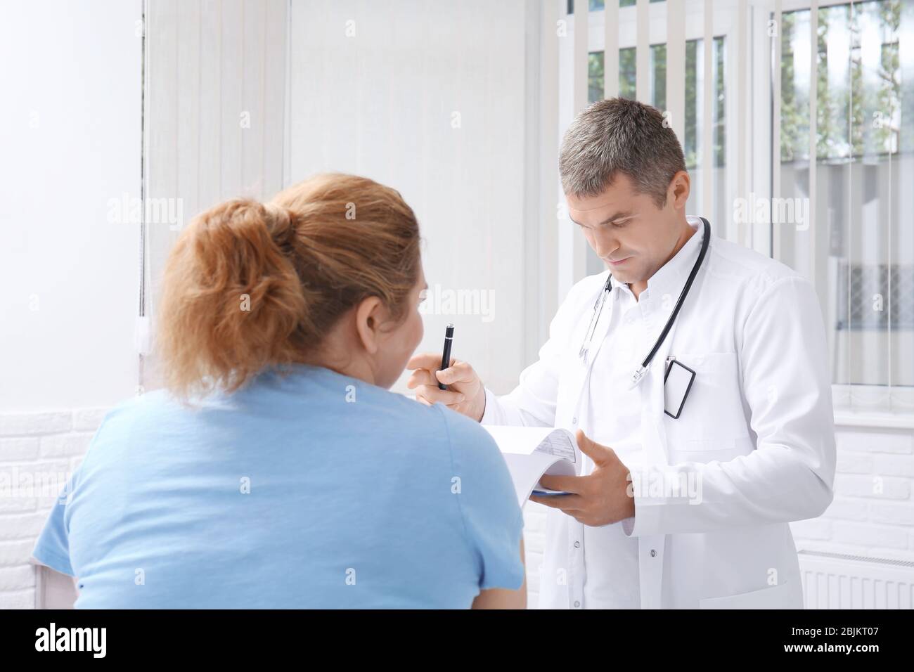 Overweight woman discussing test results with doctor in hospital Stock ...