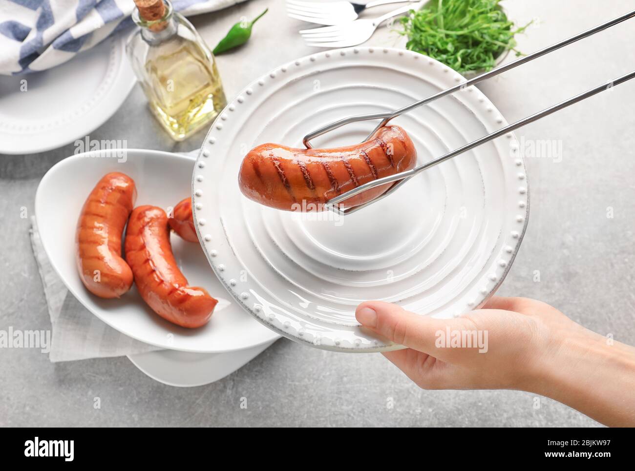 Tongs putting sausages on grill hi-res stock photography and images - Alamy