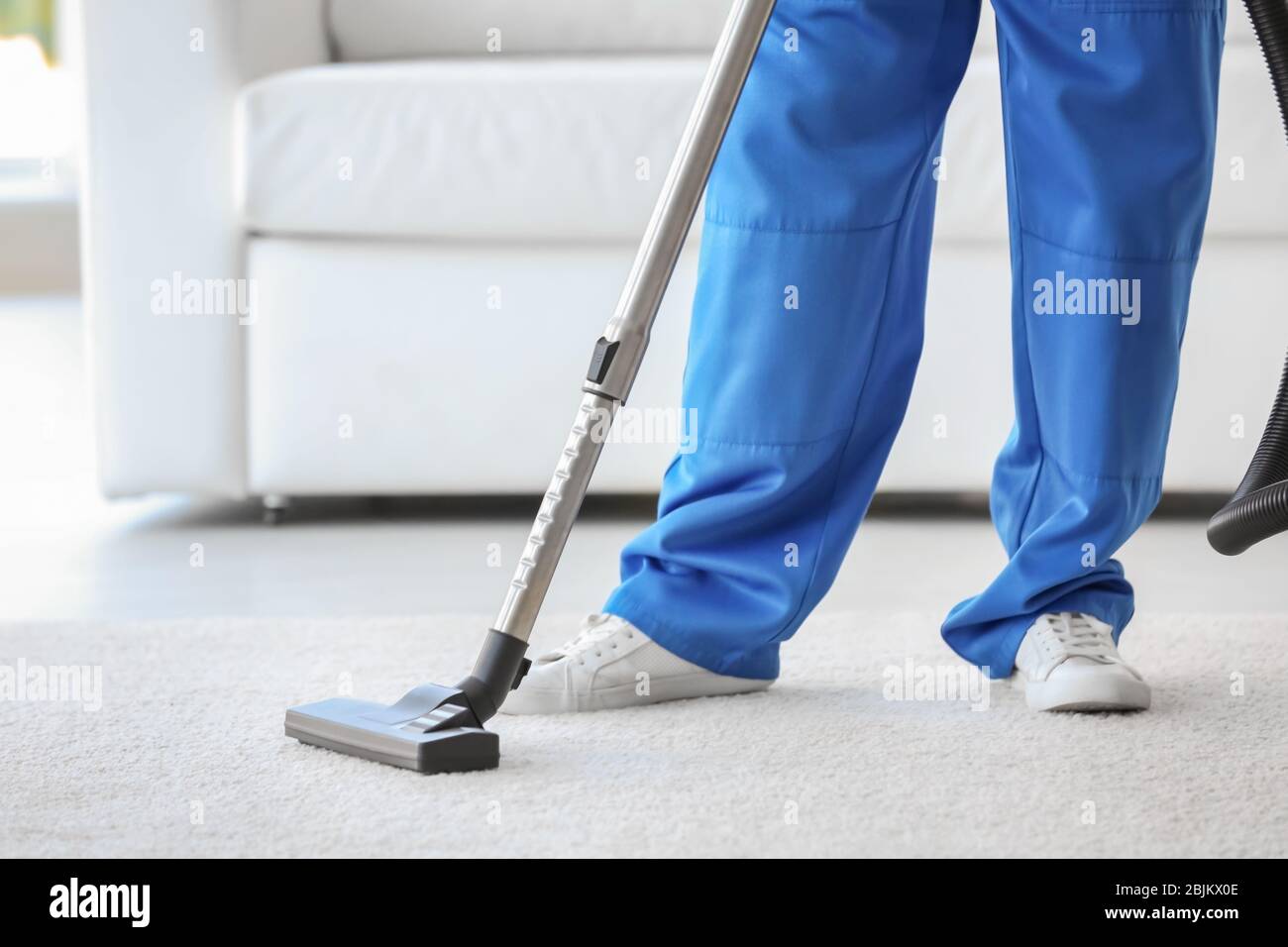 Man cleaning white carpet with vacuum in living room Stock Photo - Alamy