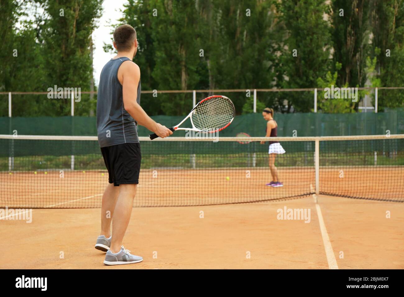 Young man and woman playing tennis on court Stock Photo - Alamy
