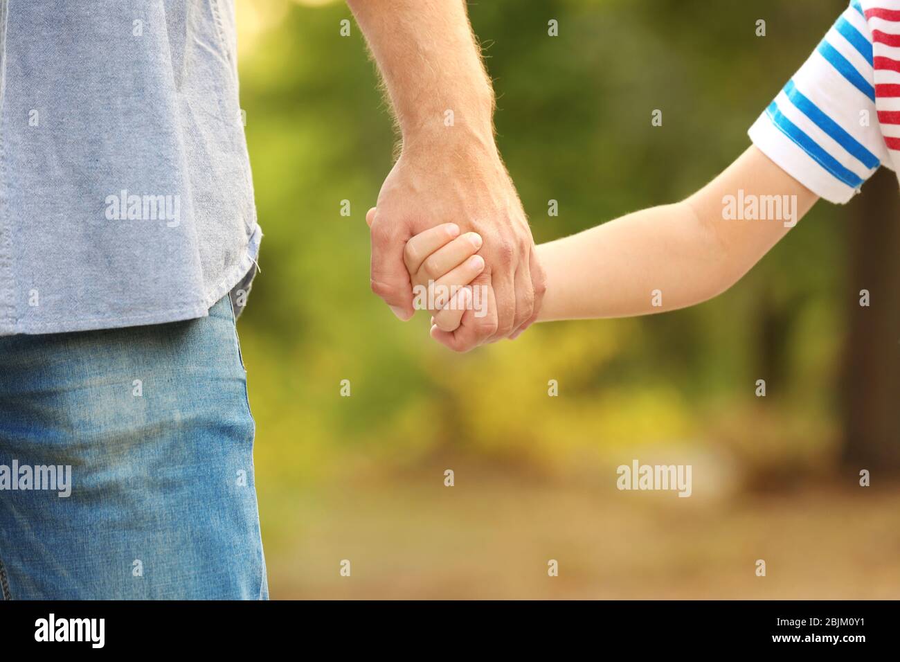Boy holding father's hand outdoors Stock Photo - Alamy