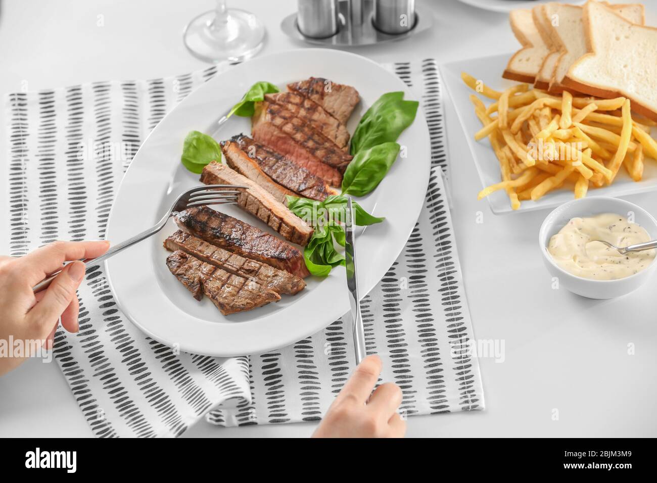 Woman eating delicious grilled steak in restaurant Stock Photo - Alamy