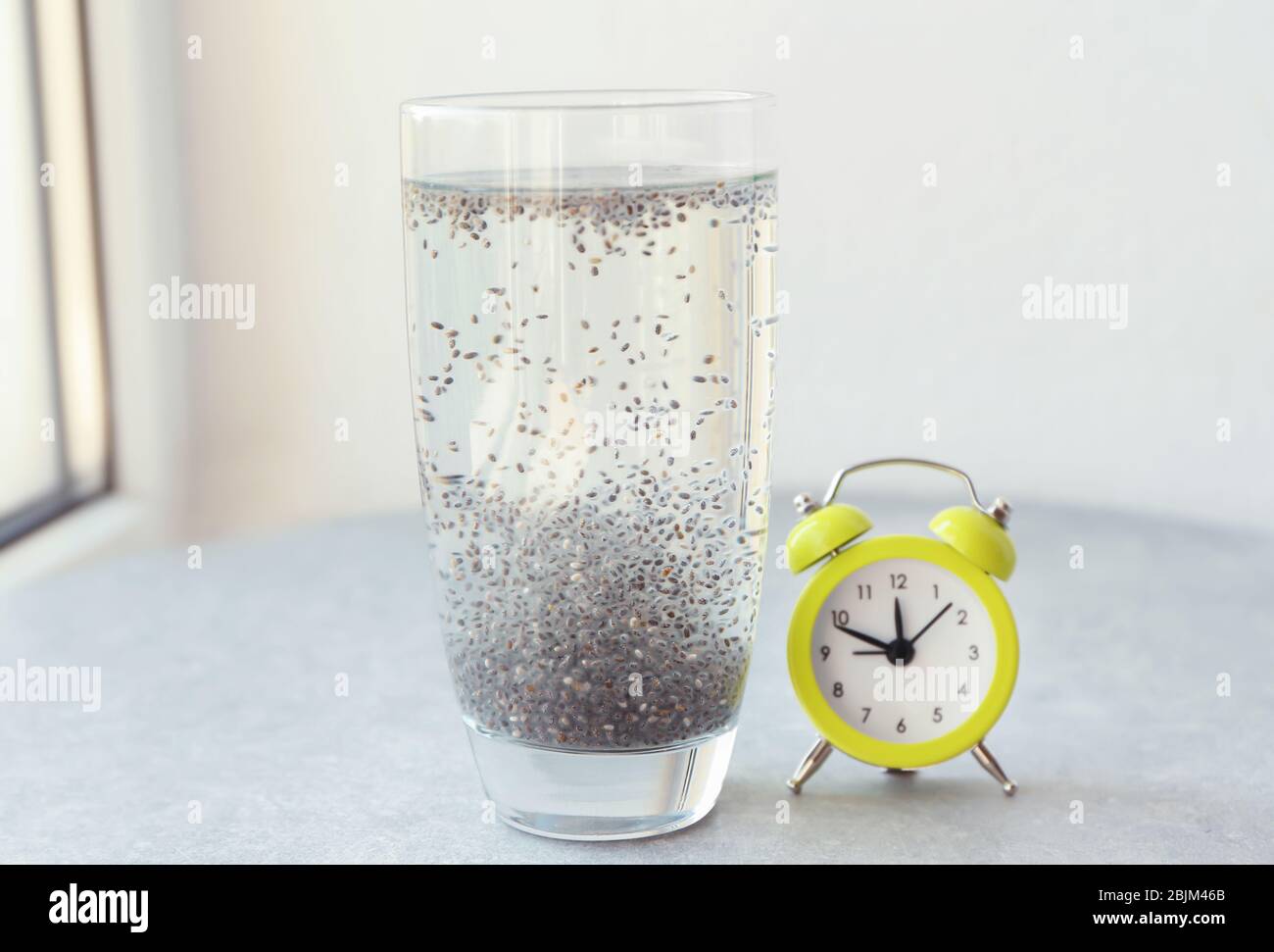 Glass of water with chia seeds and alarm clock on windowsill Stock ...