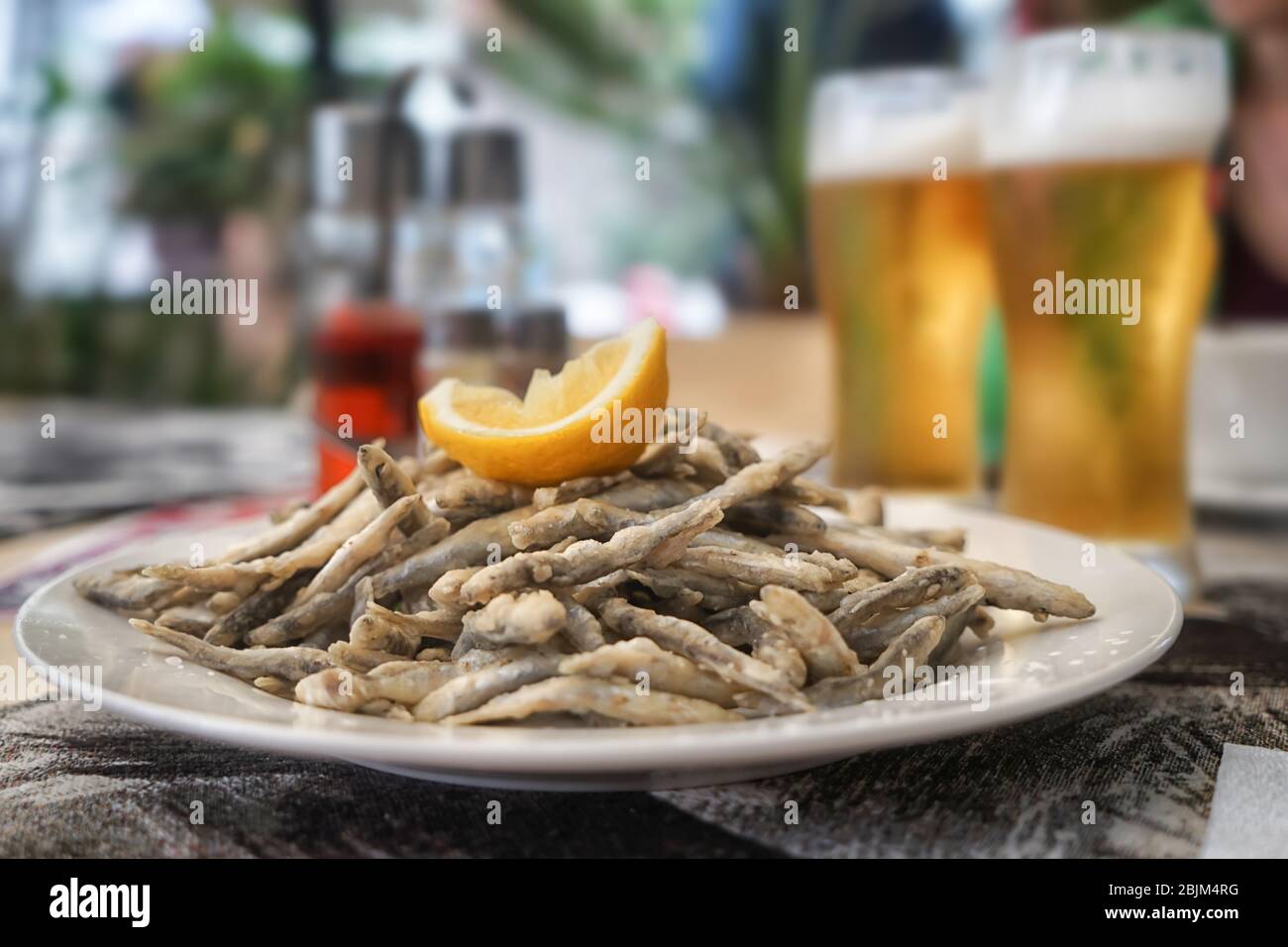 Plate with fried anchovies on table in restaurant Stock Photo - Alamy