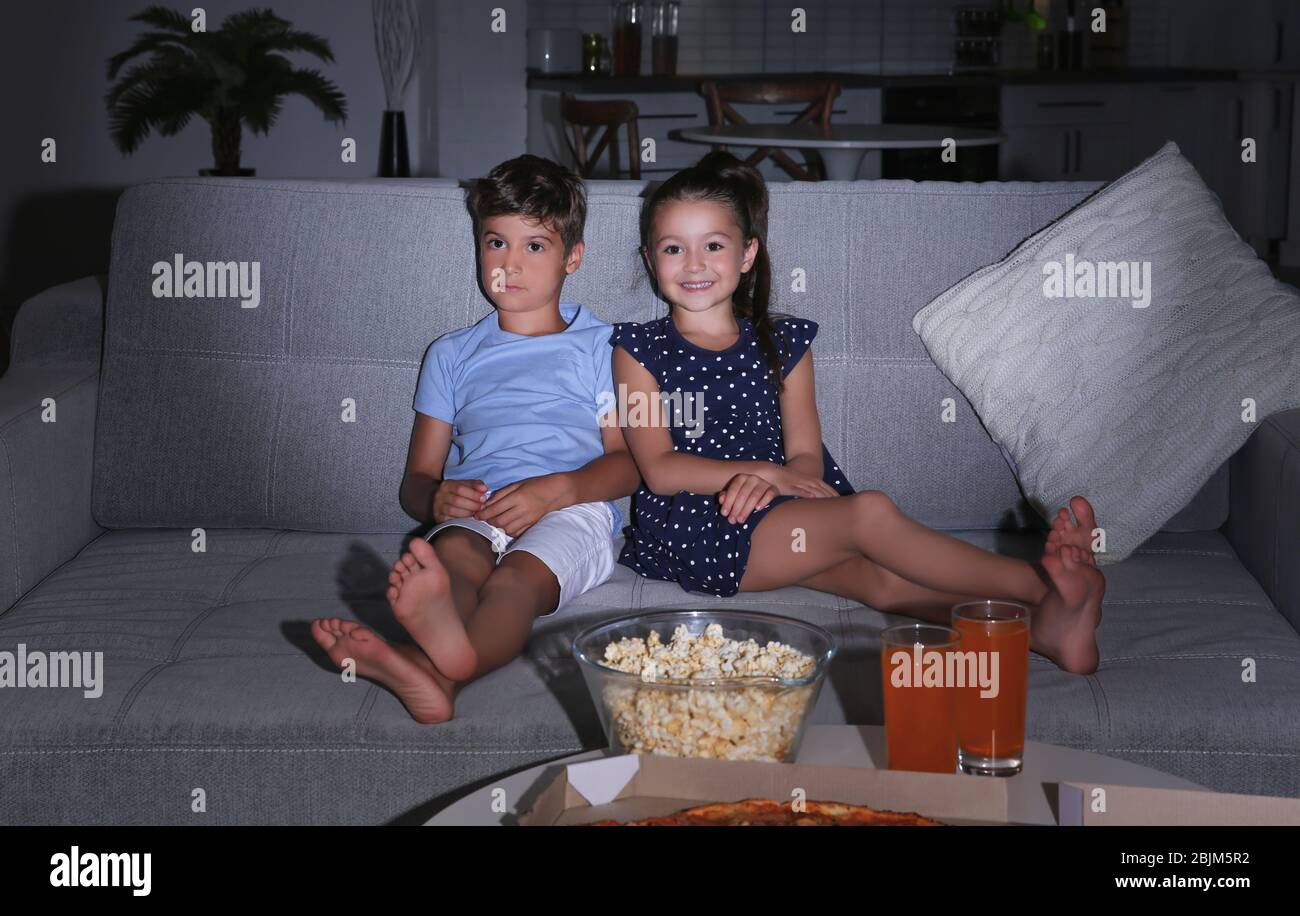 Cute children watching TV on sofa at night Stock Photo - Alamy