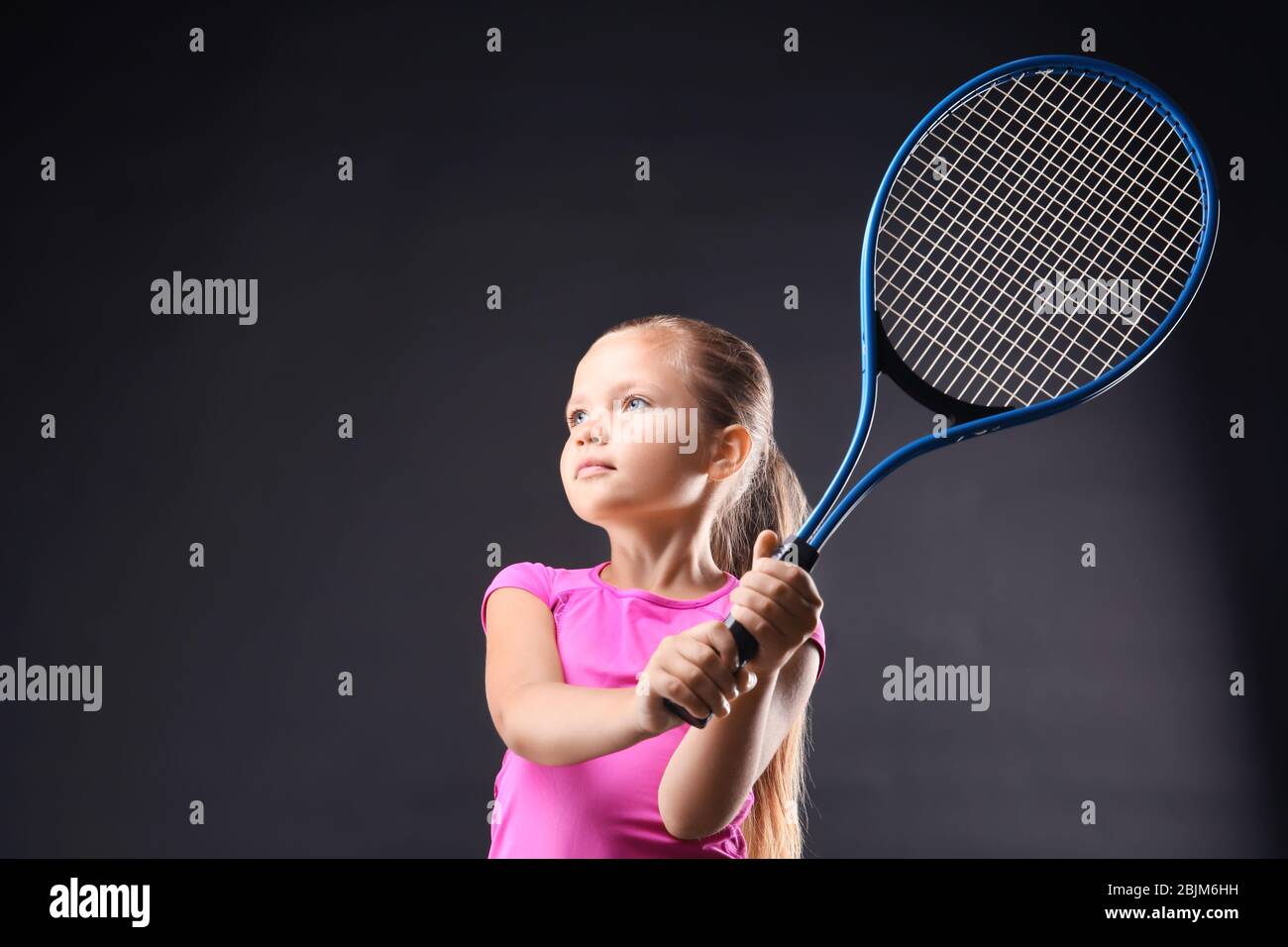 Cute little girl with tennis racket on dark background Stock Photo - Alamy
