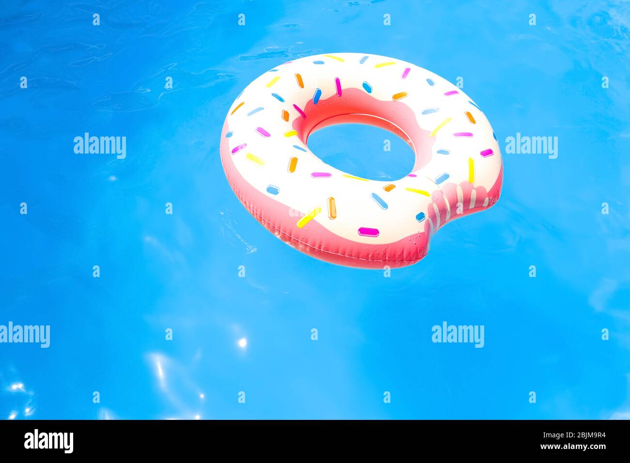 Colorful inflatable donut floating in pool Stock Photo - Alamy