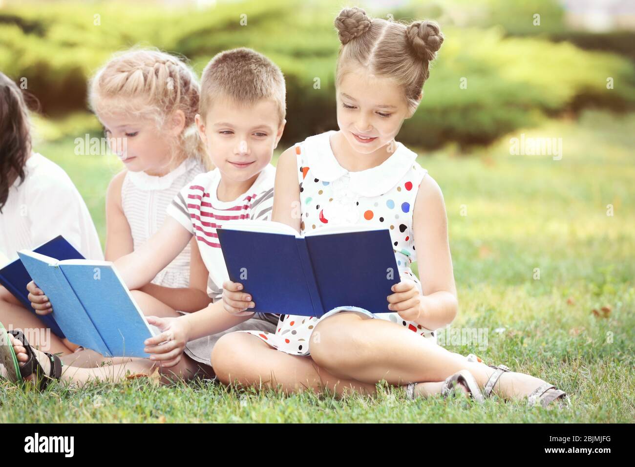 Cute little children reading books in park Stock Photo - Alamy
