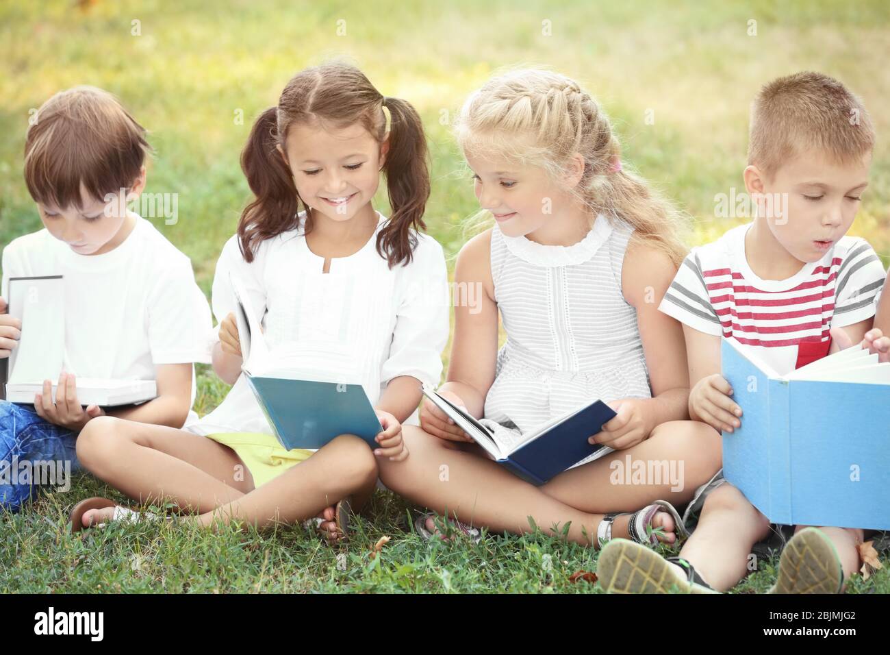 Cute little children reading books in park Stock Photo - Alamy