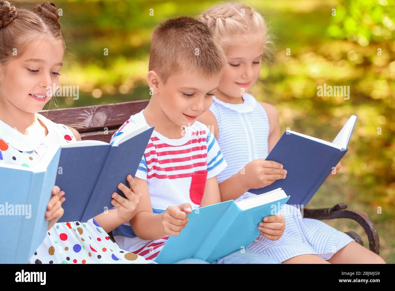 Cute little children reading books in park Stock Photo - Alamy