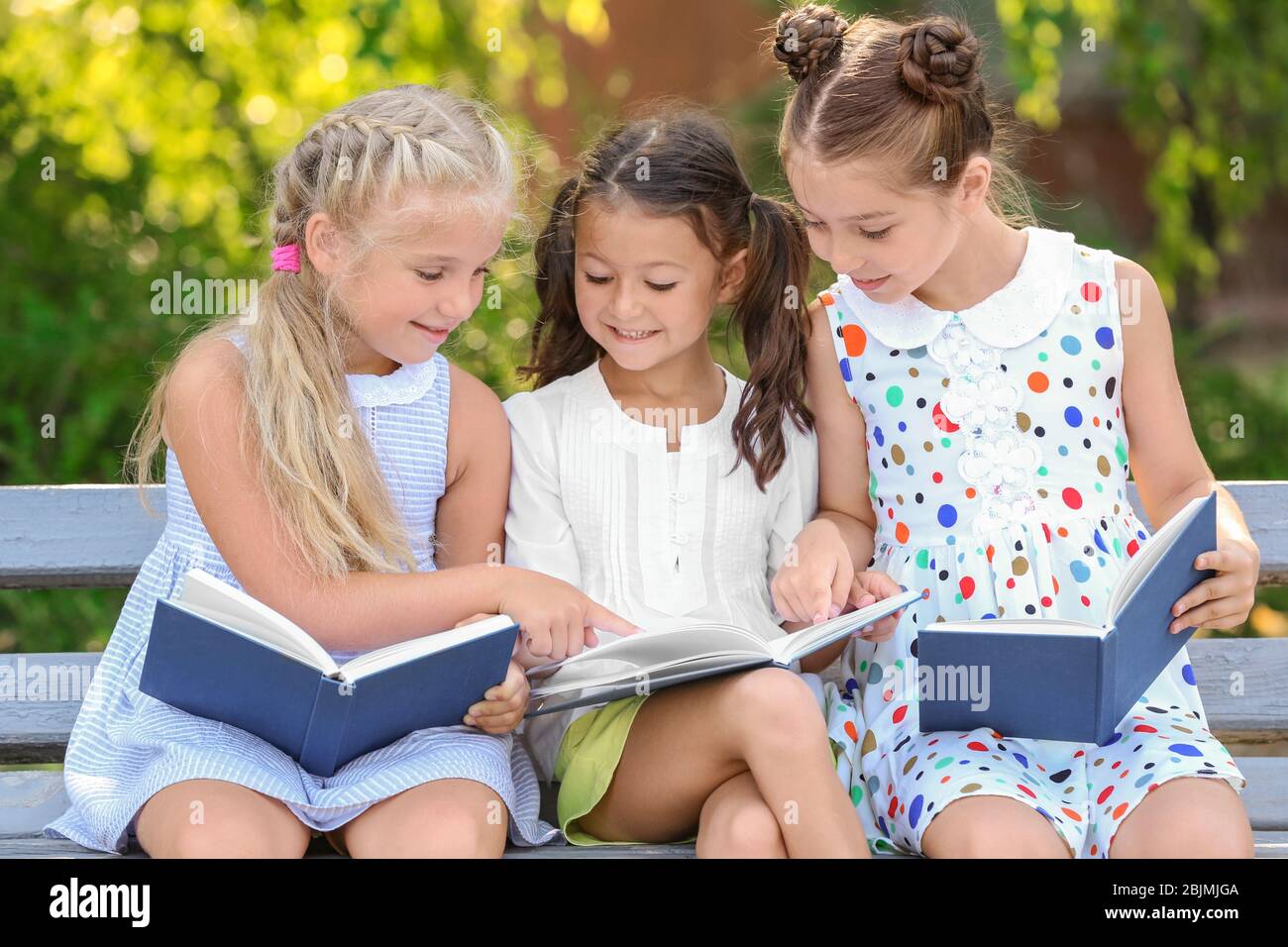 Cute little children reading books in park Stock Photo - Alamy