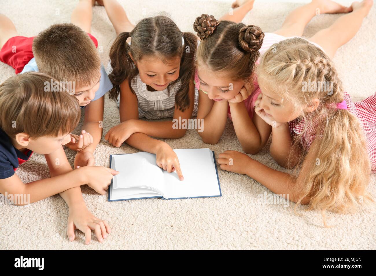 Cute little children reading book indoors Stock Photo - Alamy