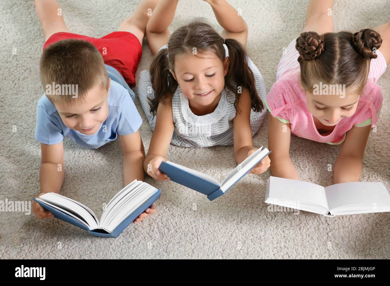 Cute little children reading books indoors Stock Photo - Alamy
