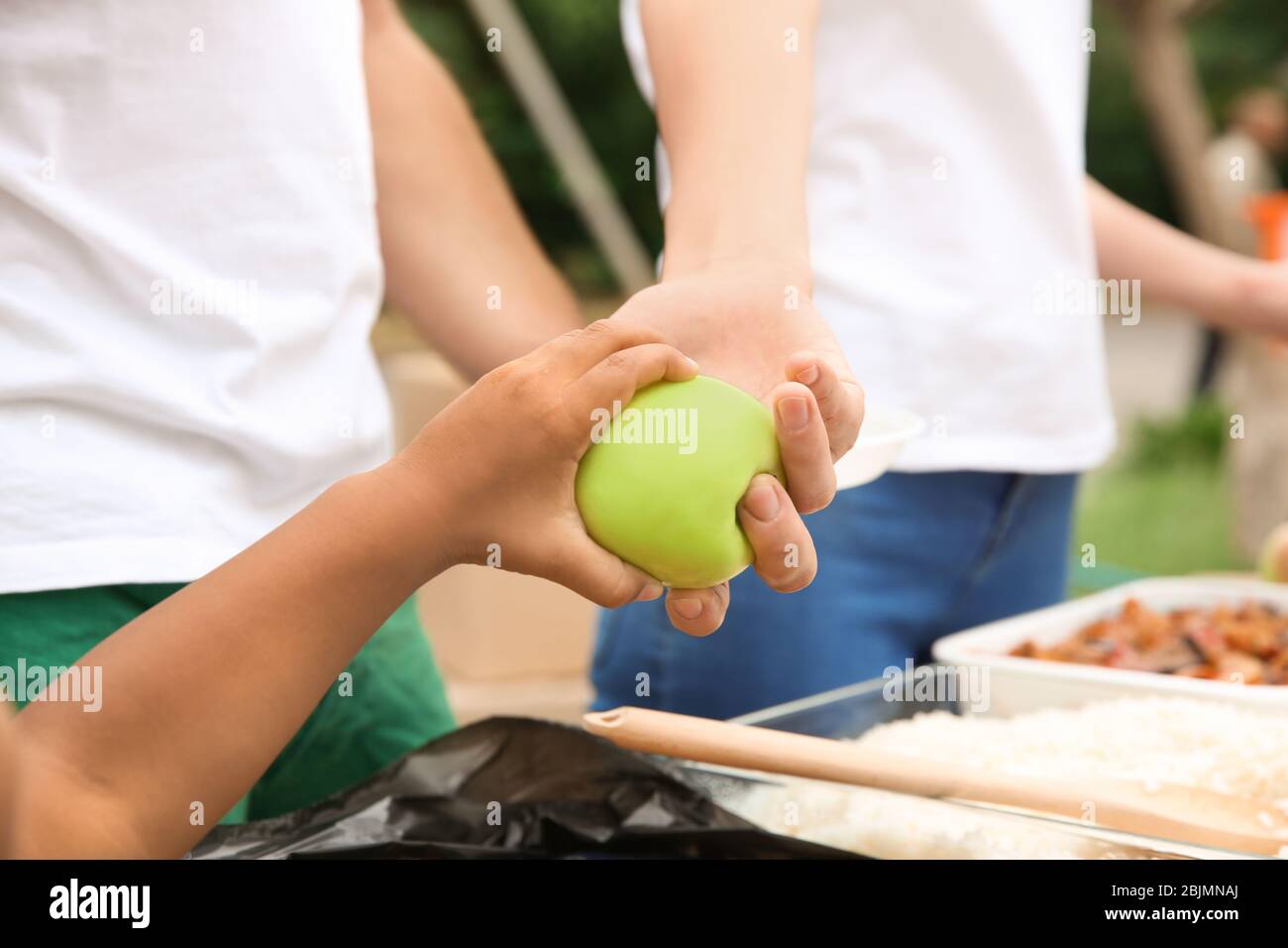 Volunteer sharing food with poor child outdoors, closeup Stock Photo ...