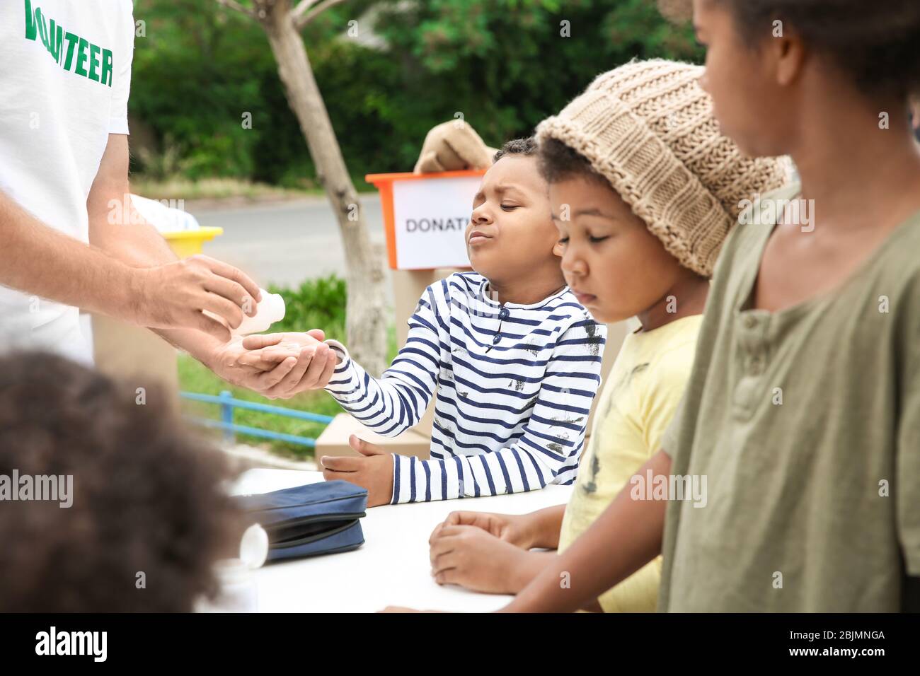 Volunteers giving vitamin tablets to poor African children outdoors ...