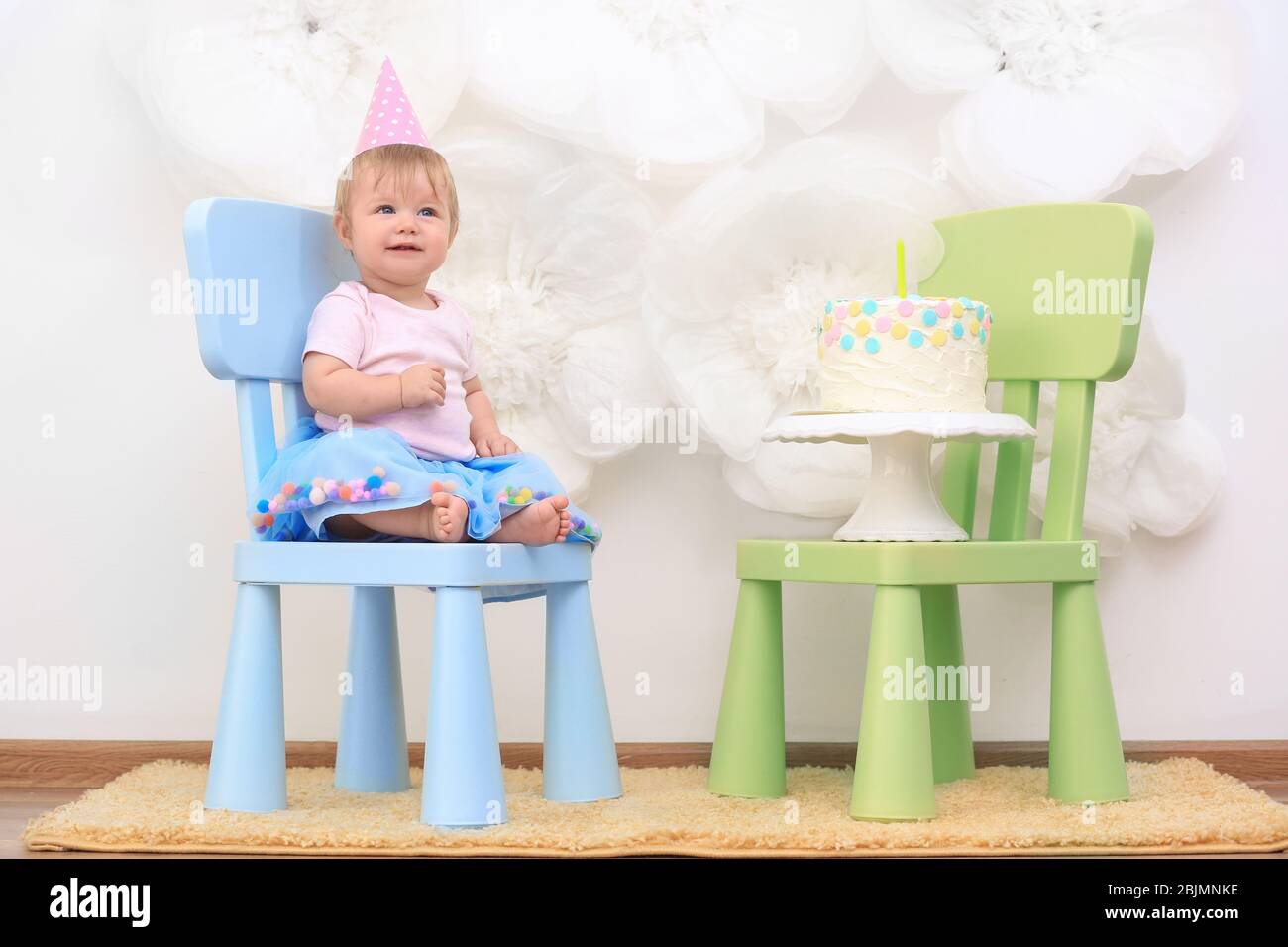 Cute little girl with delicious cake sitting on chair in room decorated ...