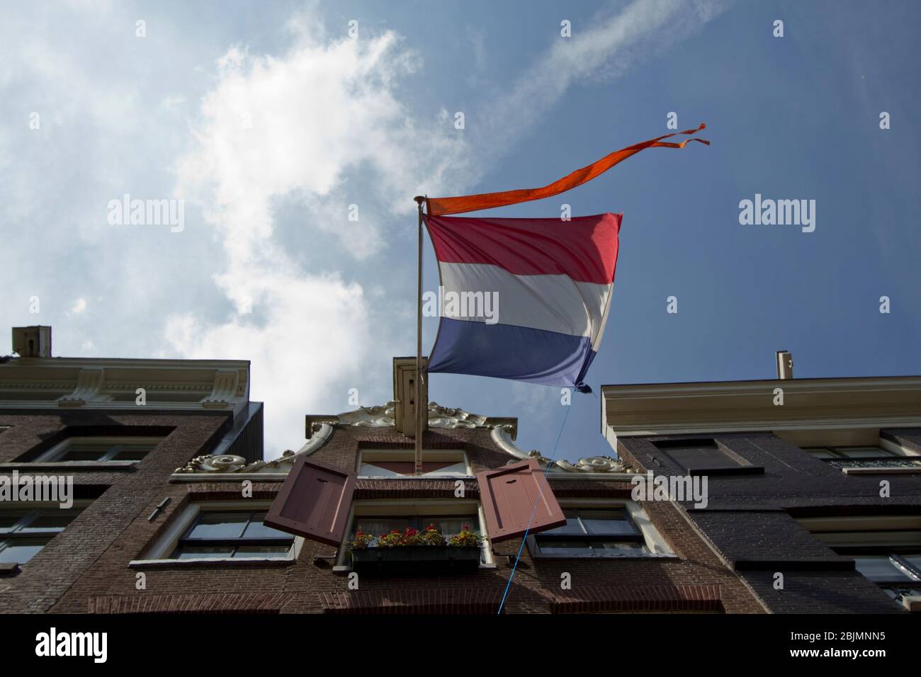 The Dutch national flag waving from a window in the center of Amsterdam ...