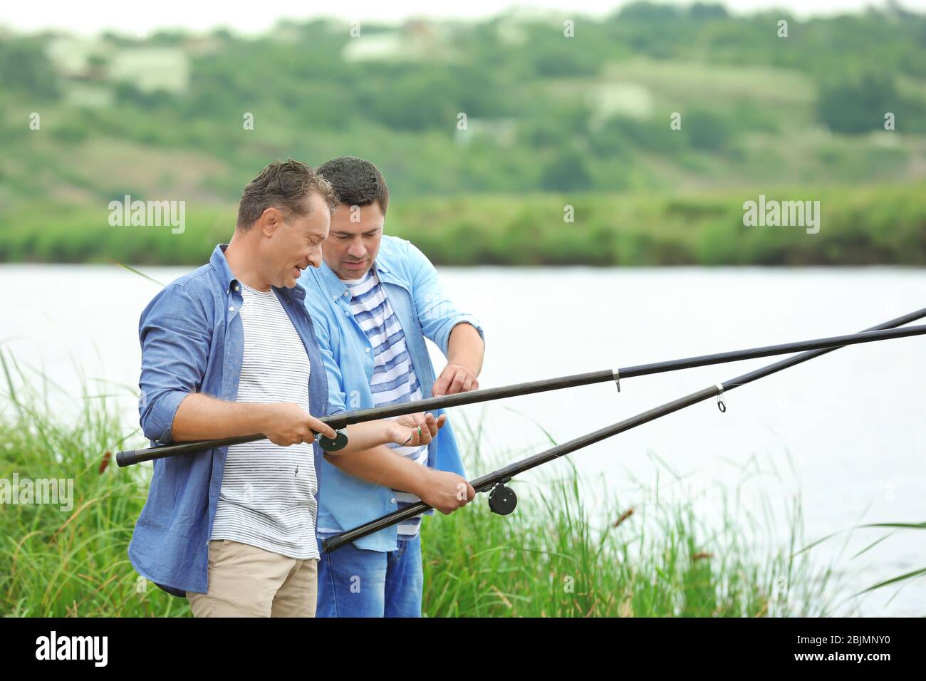 Men fishing from shore on river Stock Photo - Alamy