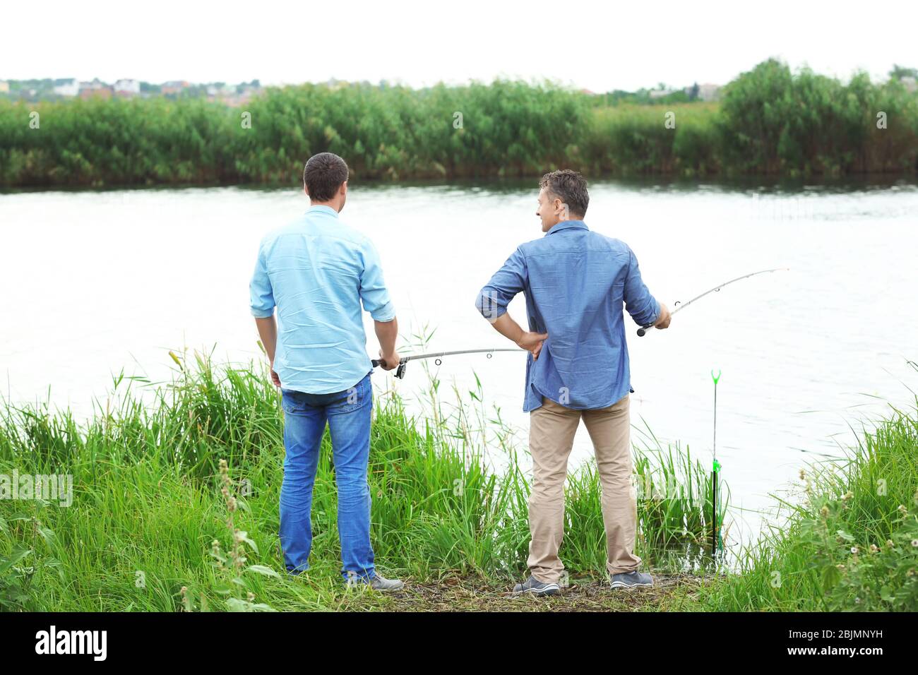 Men fishing from shore on river Stock Photo - Alamy