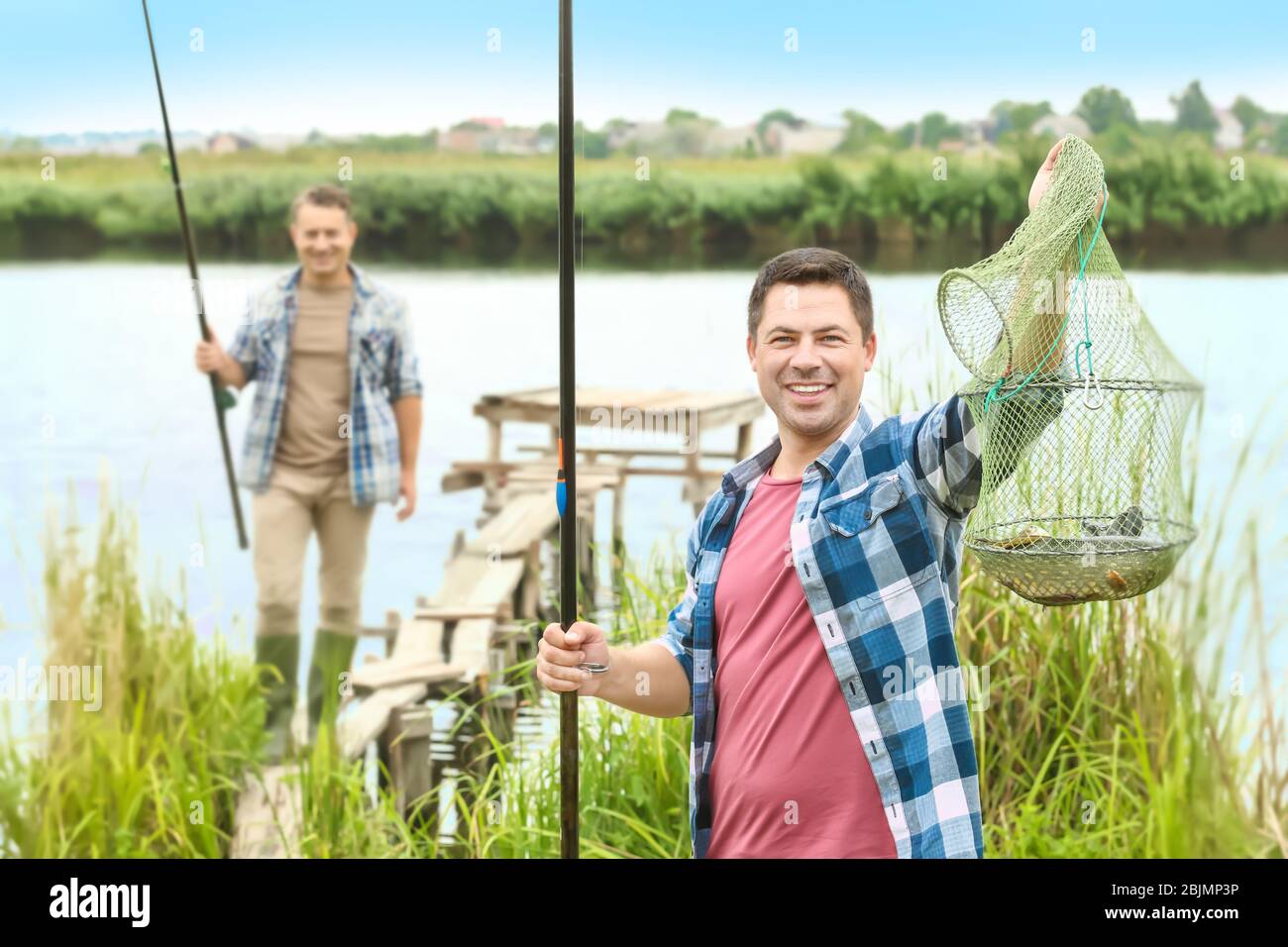Two fishermen with freshly caught fish on pier Stock Photo - Alamy