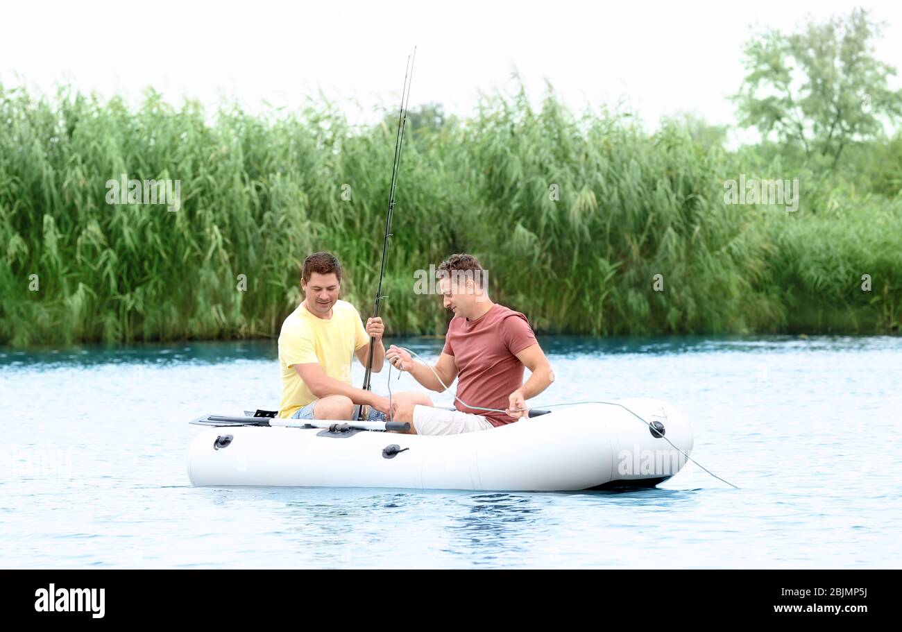 Two men fishing from inflatable boat on river Stock Photo - Alamy
