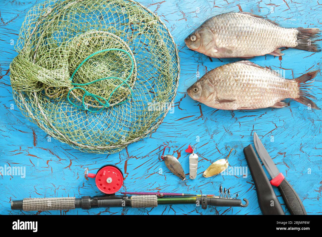 Fishing equipment and fresh fish on wooden table Stock Photo - Alamy