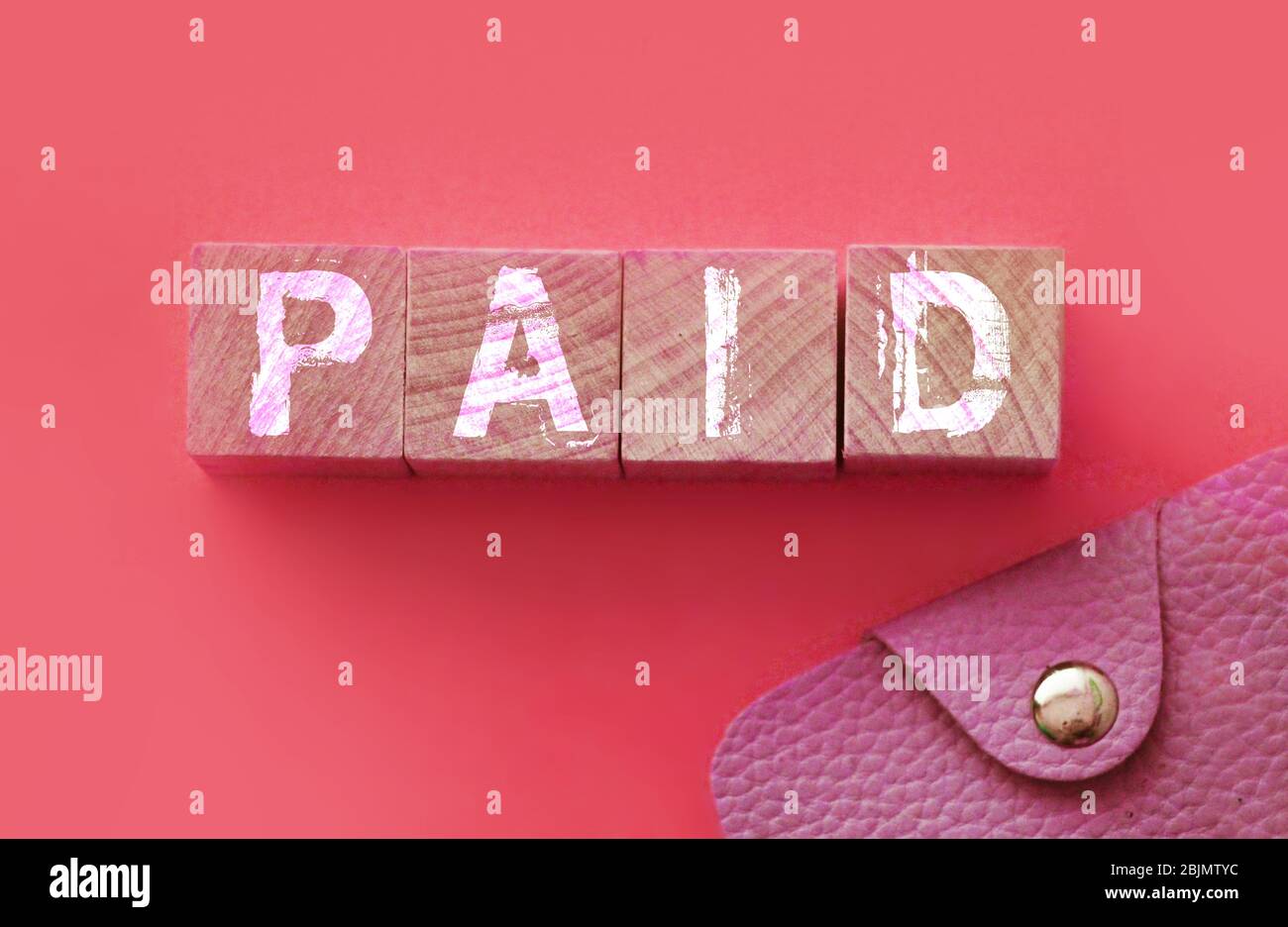 Paid word from wooden blocks and pink wallet on pink background. Taxes ...