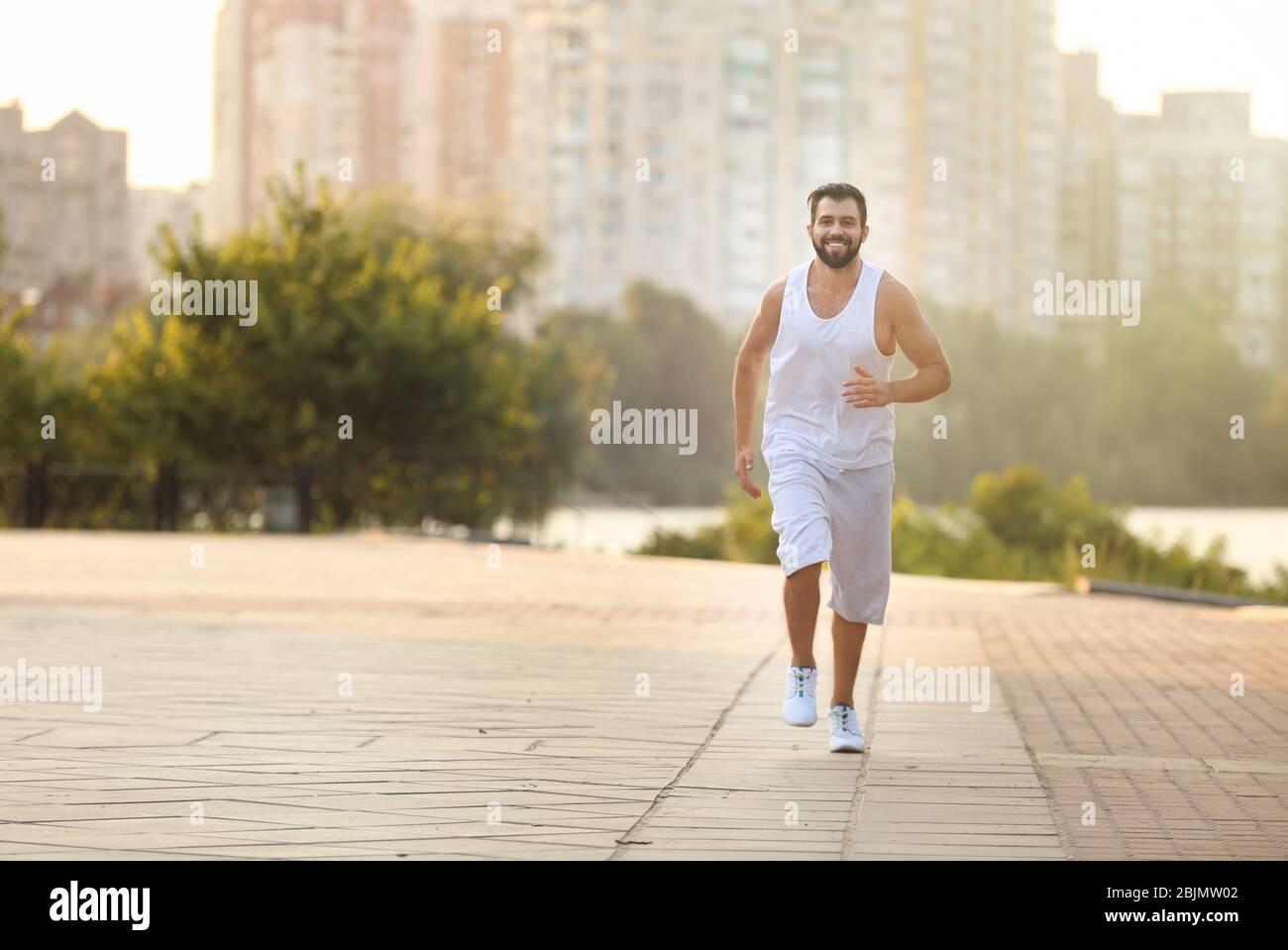 Handsome young man jogging on street Stock Photo - Alamy