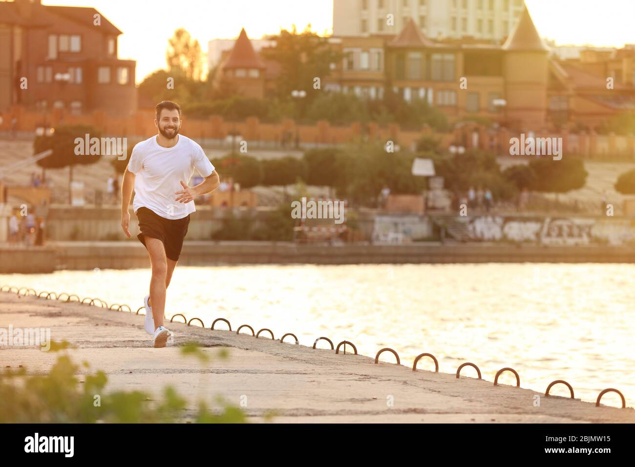 Handsome young man running near river Stock Photo - Alamy