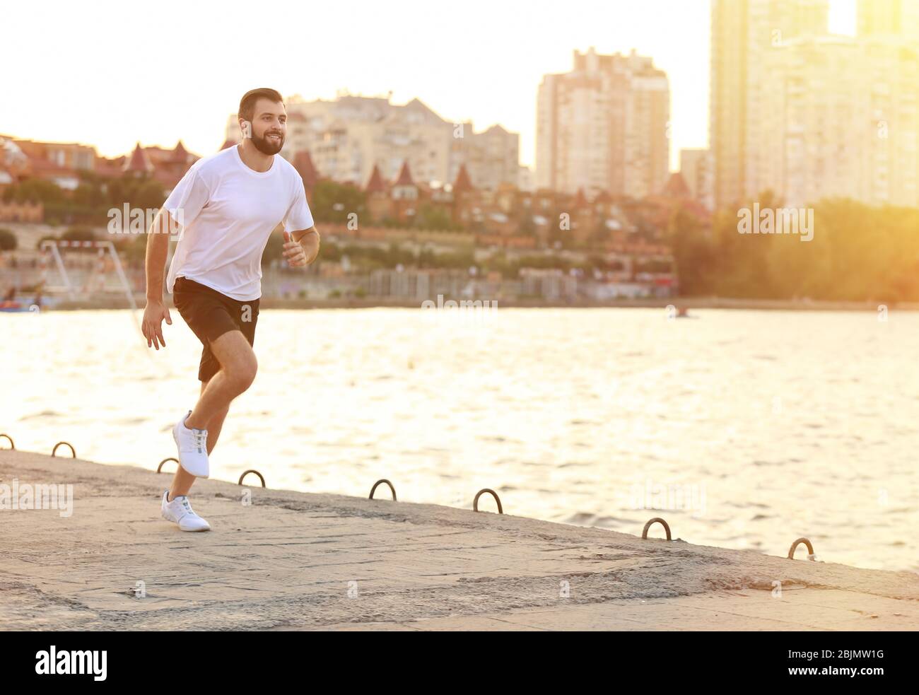 Handsome young man running near river Stock Photo - Alamy