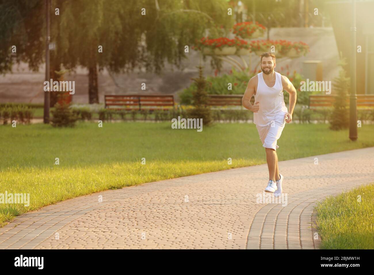 Handsome young man jogging in park Stock Photo - Alamy