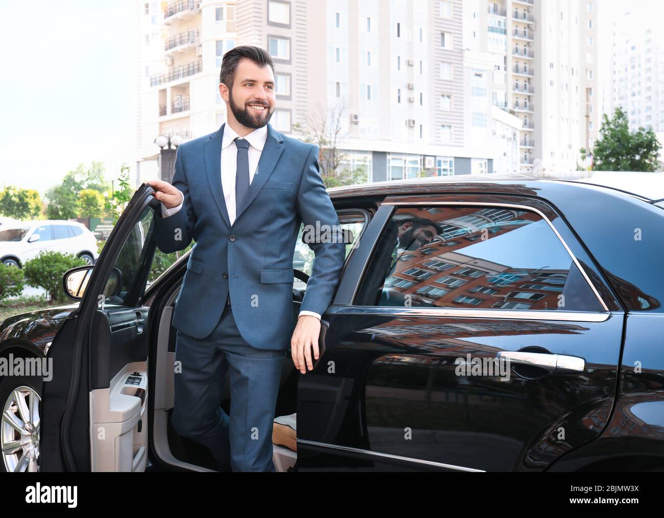 Handsome man in suit getting out of car Stock Photo - Alamy