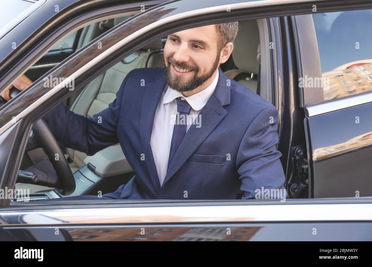 Handsome man in suit getting out of car Stock Photo - Alamy