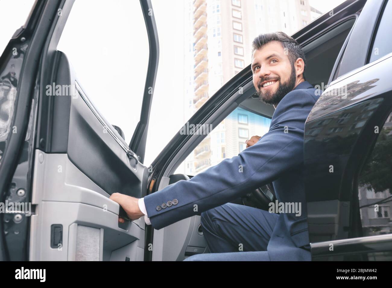 Handsome man in suit getting out of car Stock Photo - Alamy