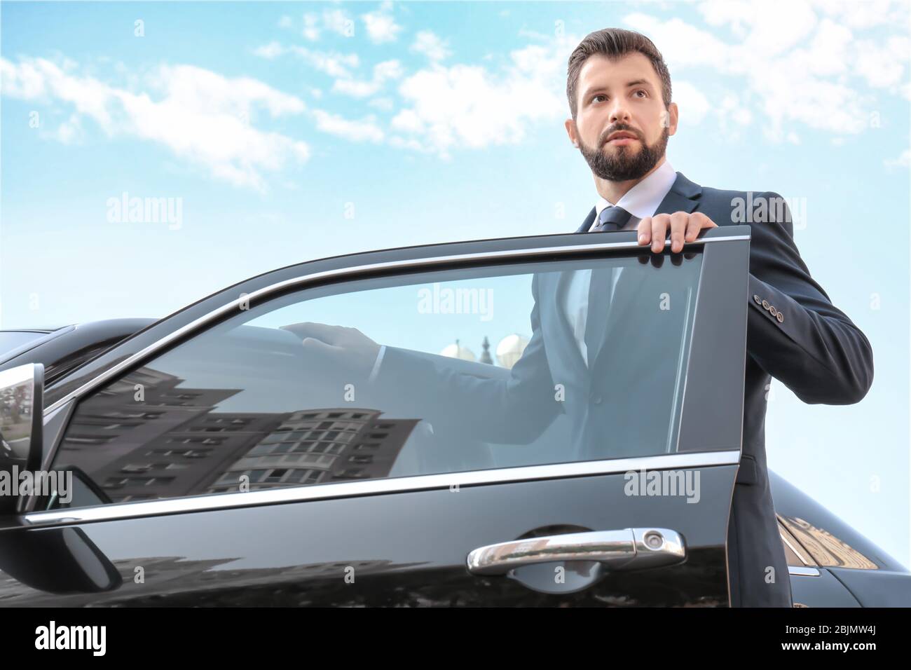 Handsome man in suit getting in car Stock Photo - Alamy