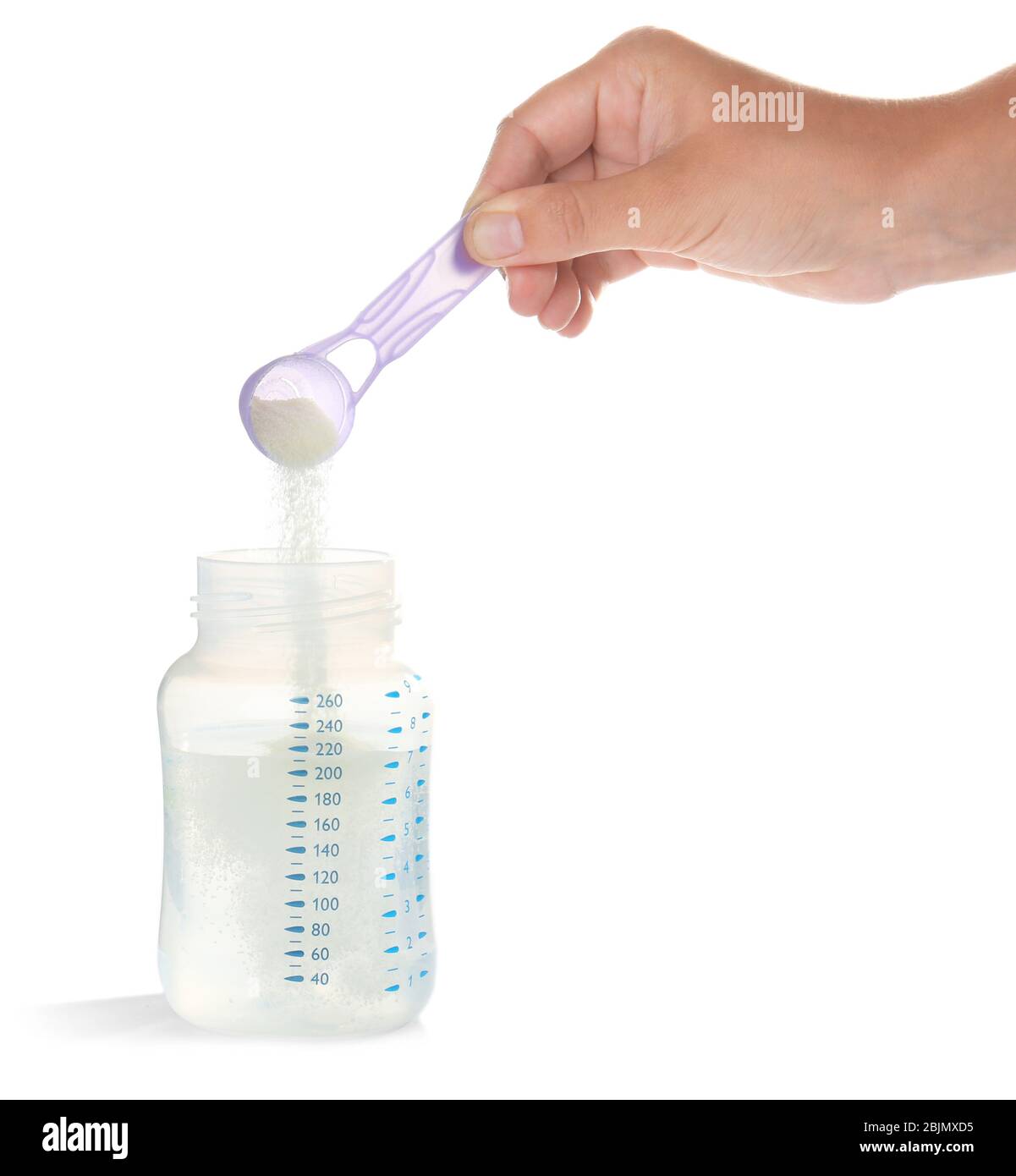 Woman's hand adding milk formula to water in baby bottle on white ...