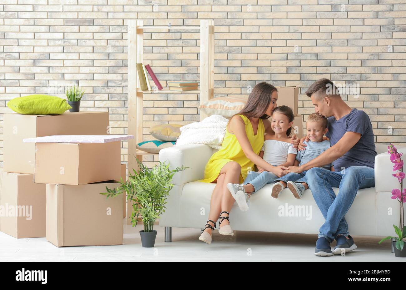 Happy family sitting on sofa in room at new home Stock Photo - Alamy