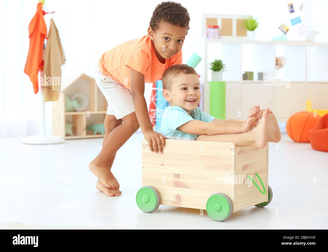 Cute children playing with wooden cart indoor Stock Photo - Alamy