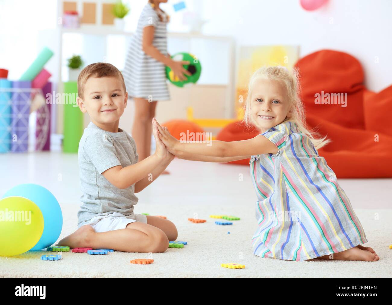 Cute children playing a clapping game indoor Stock Photo - Alamy