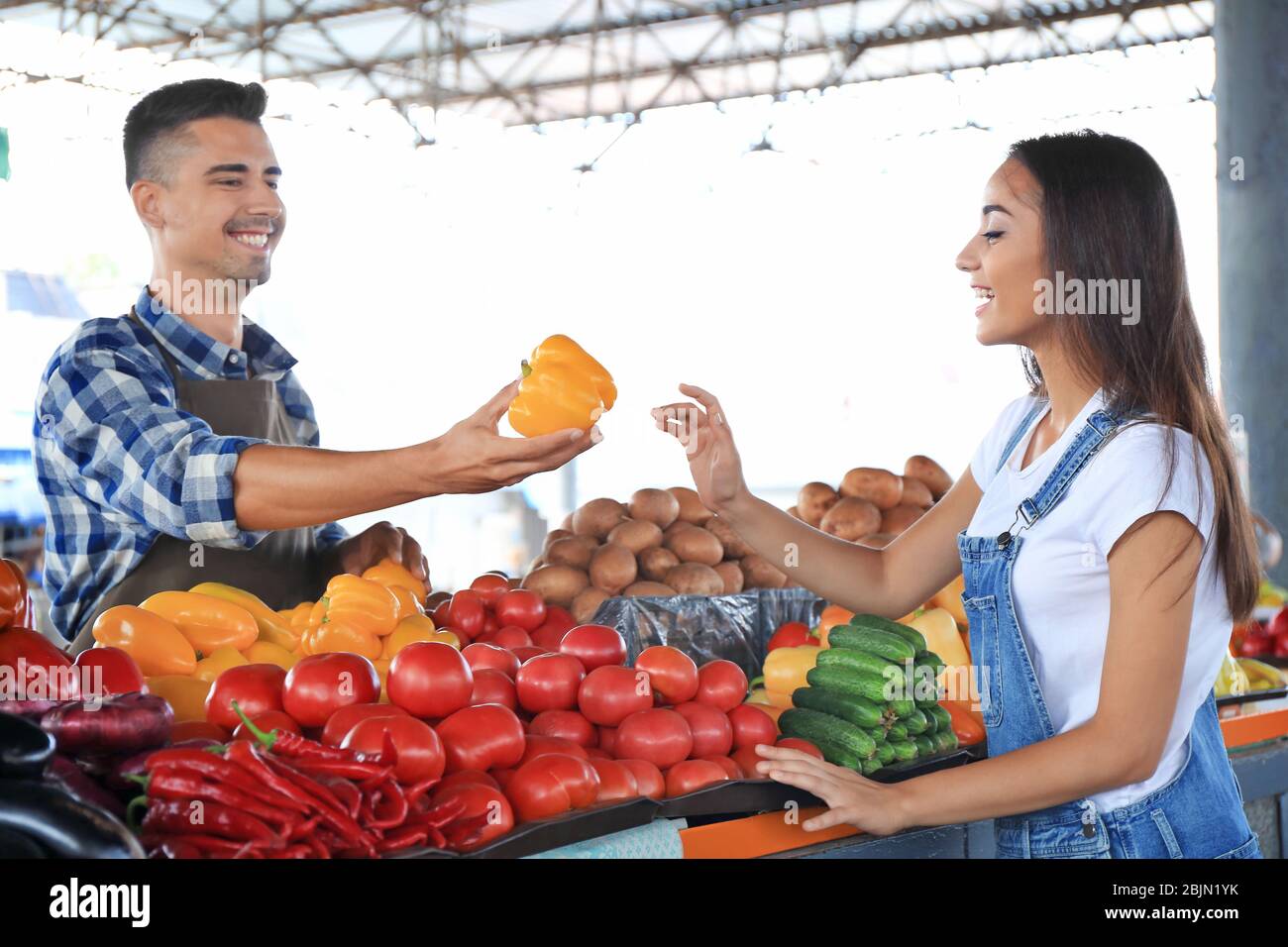 Salesman helping customer choosing vegetables at market Stock Photo - Alamy