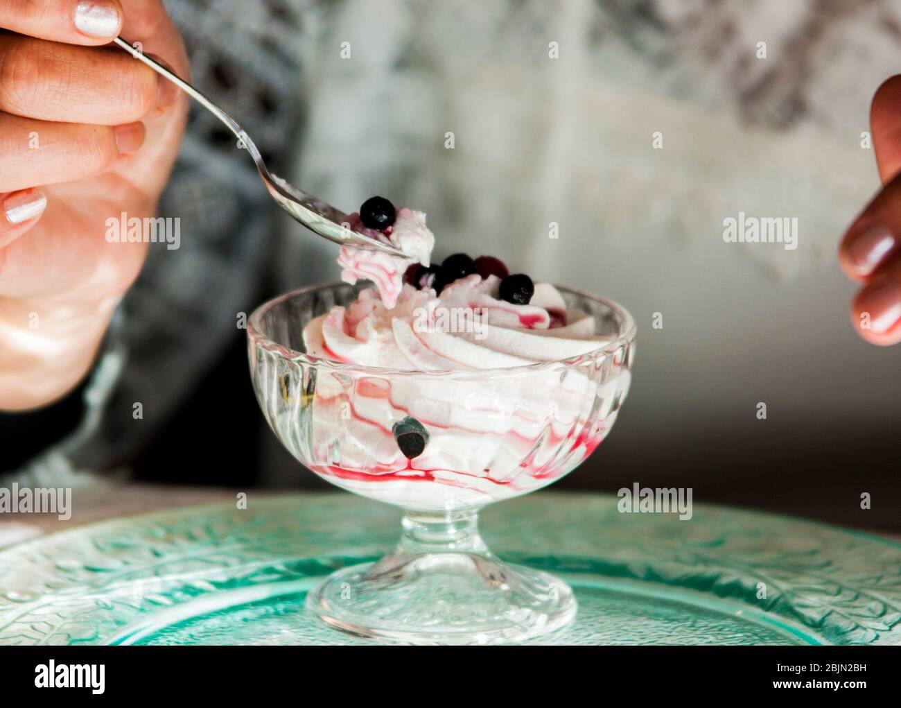 Woman eating a whipped vanilla cream dessert with syrup and blueberries ...