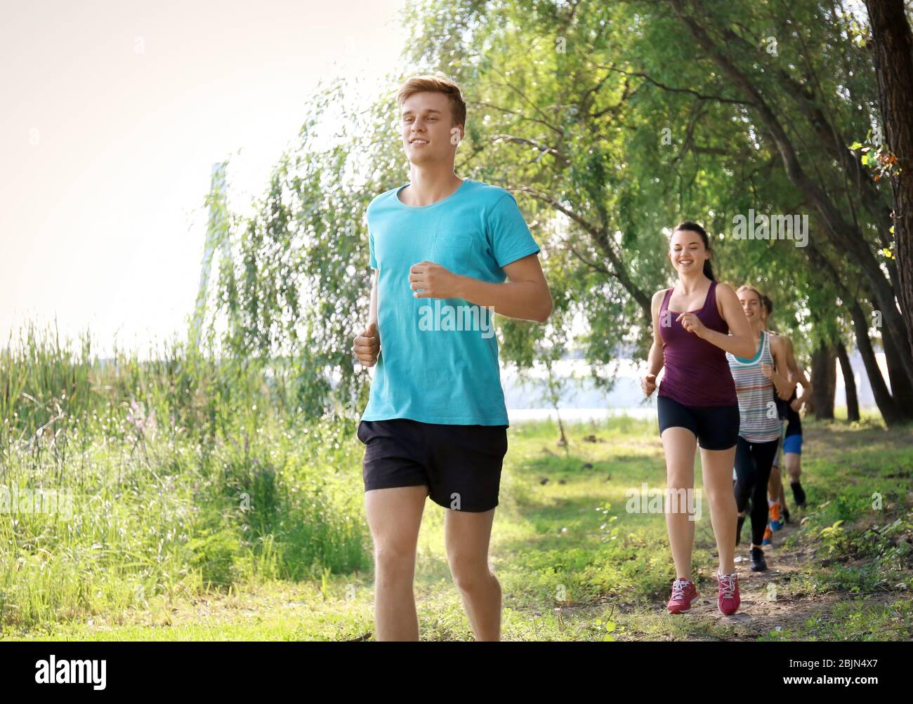 Group of young people running in park Stock Photo - Alamy