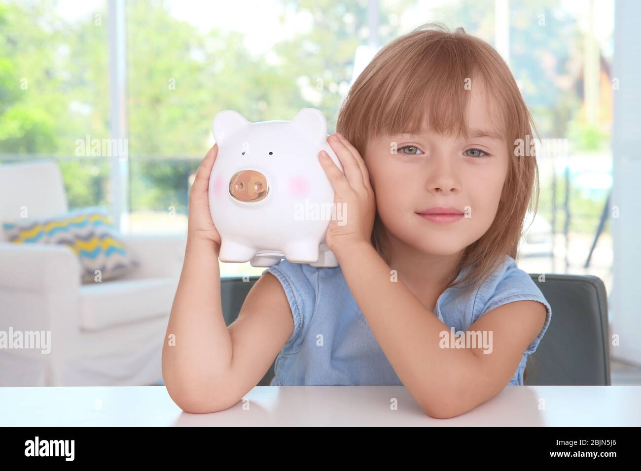Cute little girl with piggy bank indoors Stock Photo - Alamy