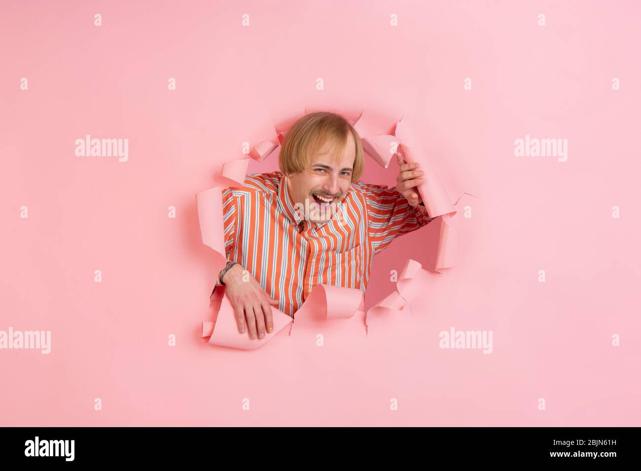 Eccentric smiling. Cheerful caucasian young man poses in torn coral ...