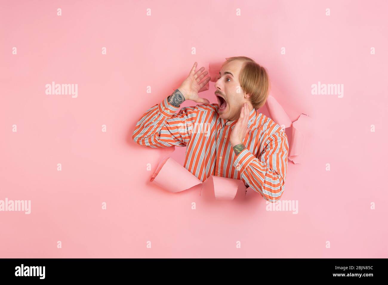 Scared screaming, shouting. Cheerful caucasian young man poses in torn ...